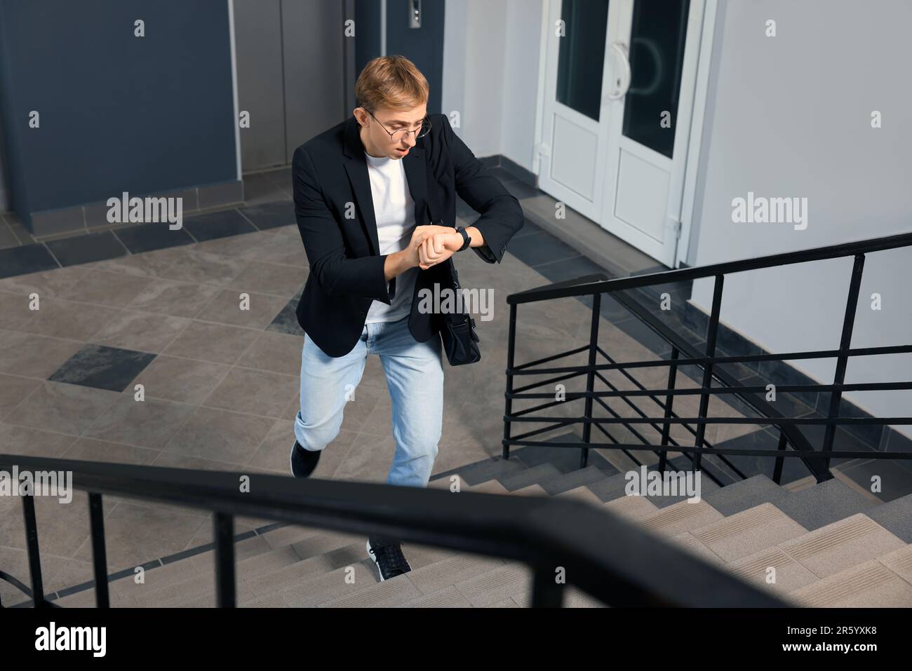 Emotional man checking time while walking up stairs in office. Being ...
