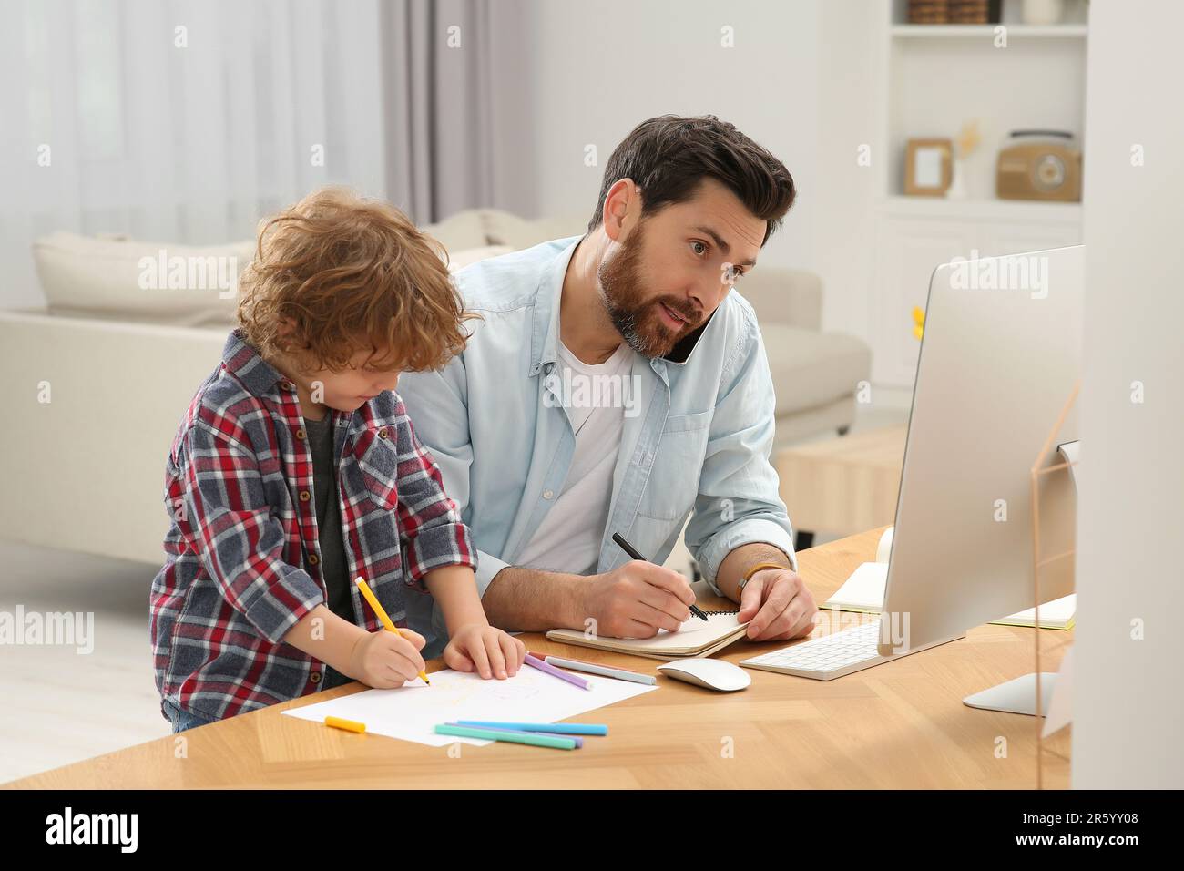 Man working remotely at home. Busy father talking on smartphone while ...
