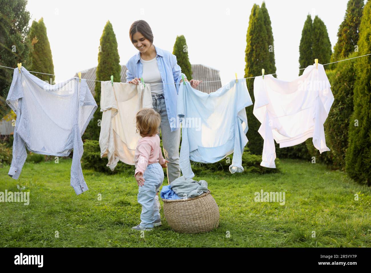 Mother and daughter near washing line with drying clothes in backyard ...