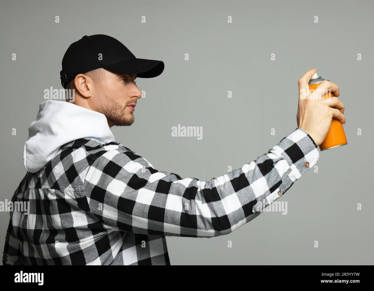 Handsome man holding orange can of spray paint on grey background Stock ...