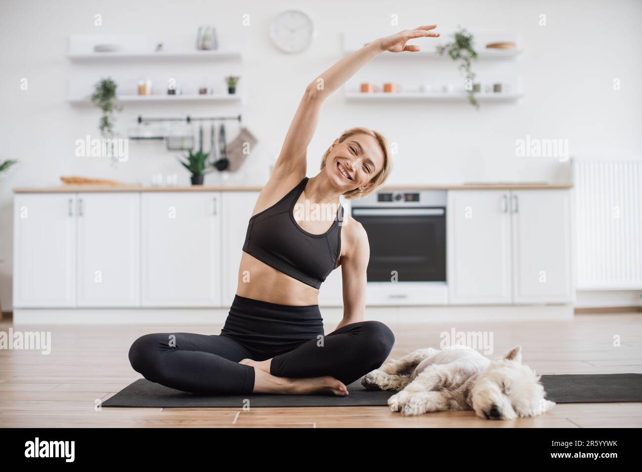 Portrait of slim woman in yoga outfit breathing in Parsva Sukhasana ...