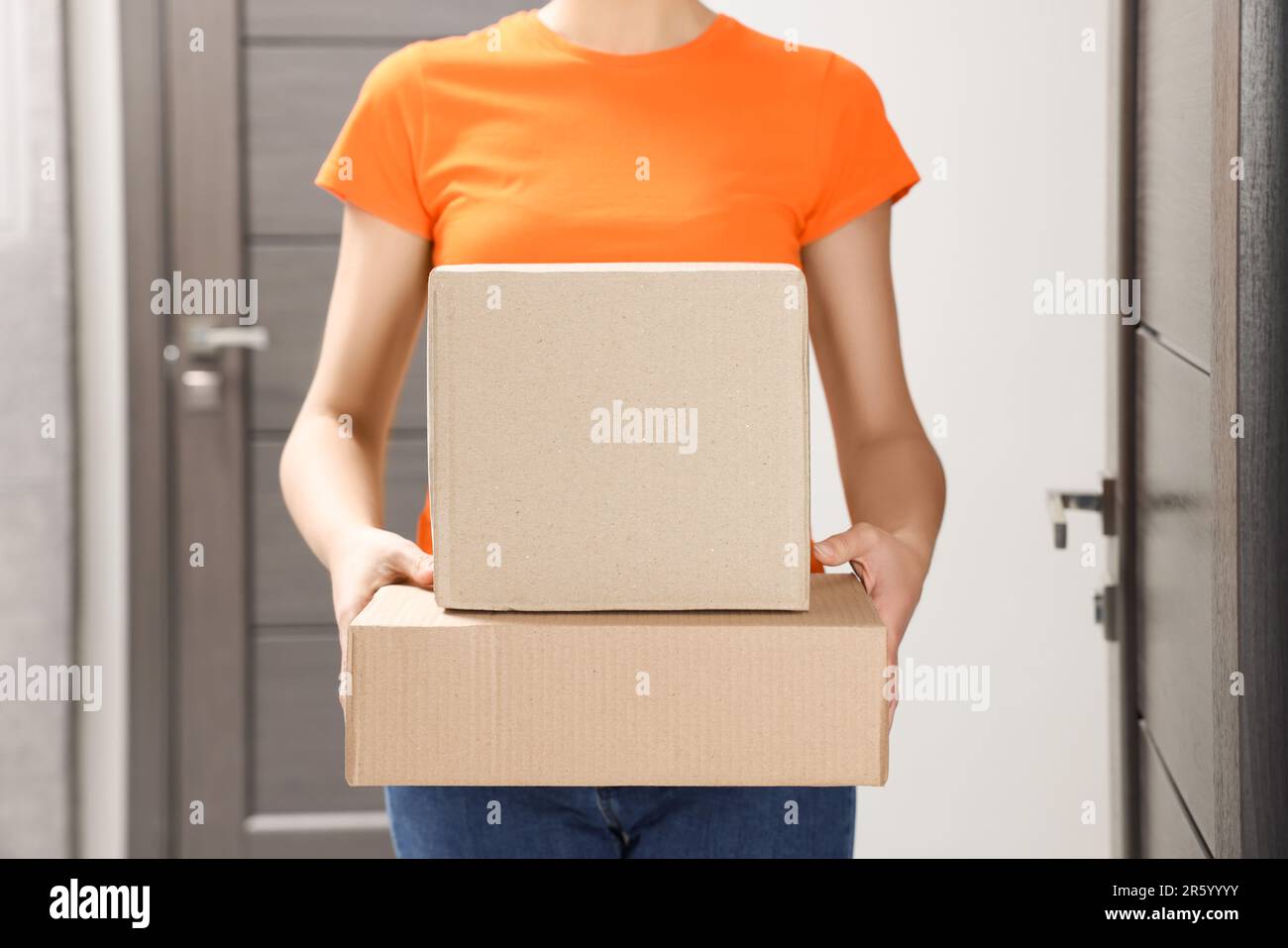Courier with cardboard boxes in hallway, closeup Stock Photo - Alamy
