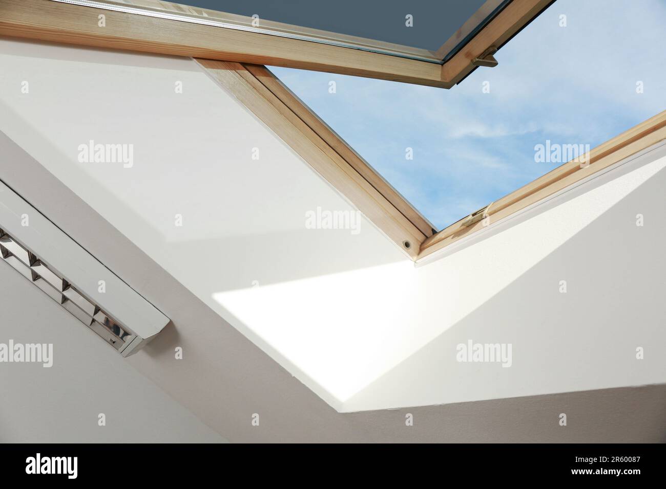 Open skylight roof window on slanted ceiling in attic room, low angle ...