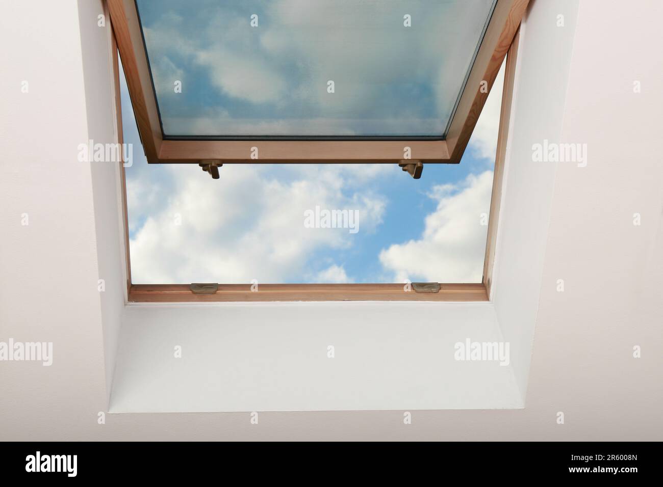 Open skylight roof window on slanted ceiling in attic room, bottom view ...