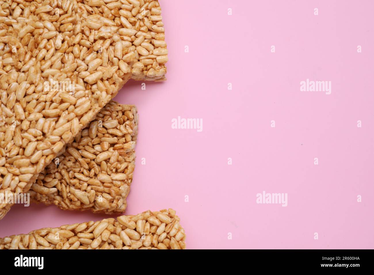 Puffed rice bars (kozinaki) on pink background, flat lay. Space for ...