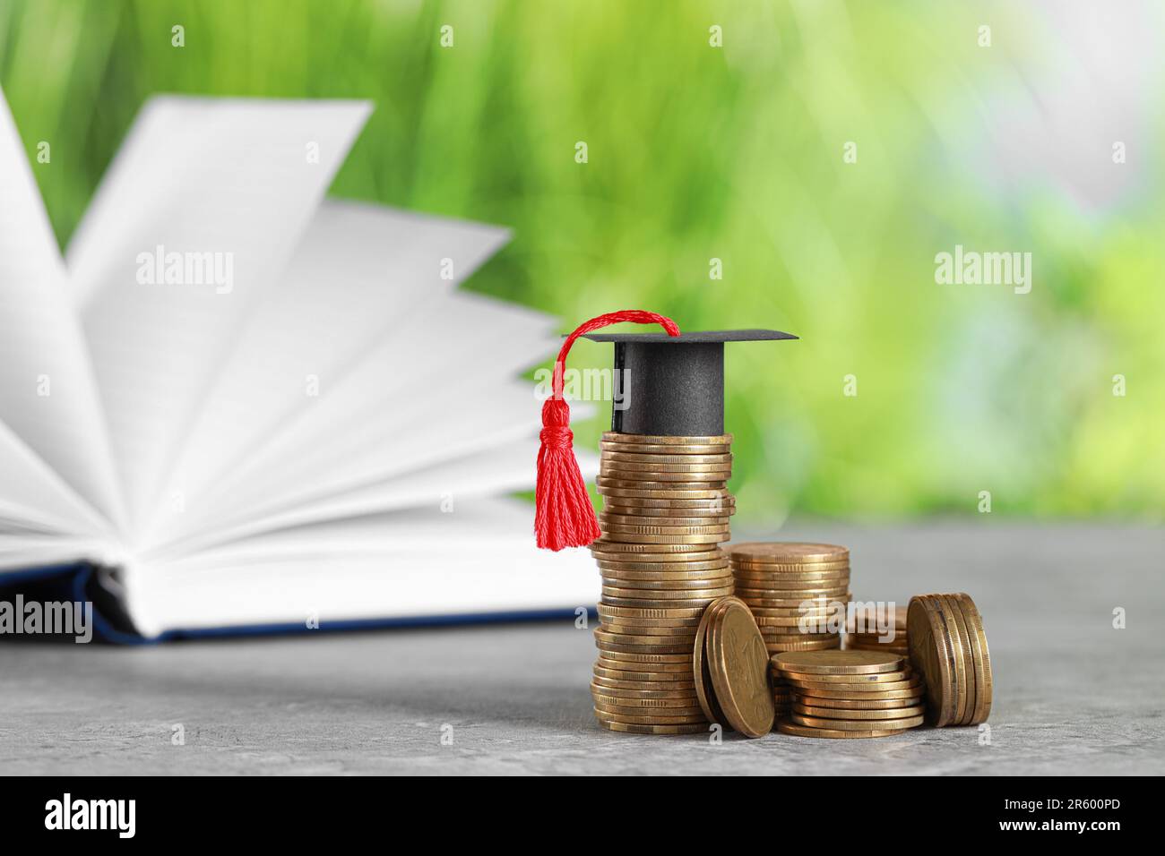 Scholarship concept. Coins and graduation cap on grey table, space for ...