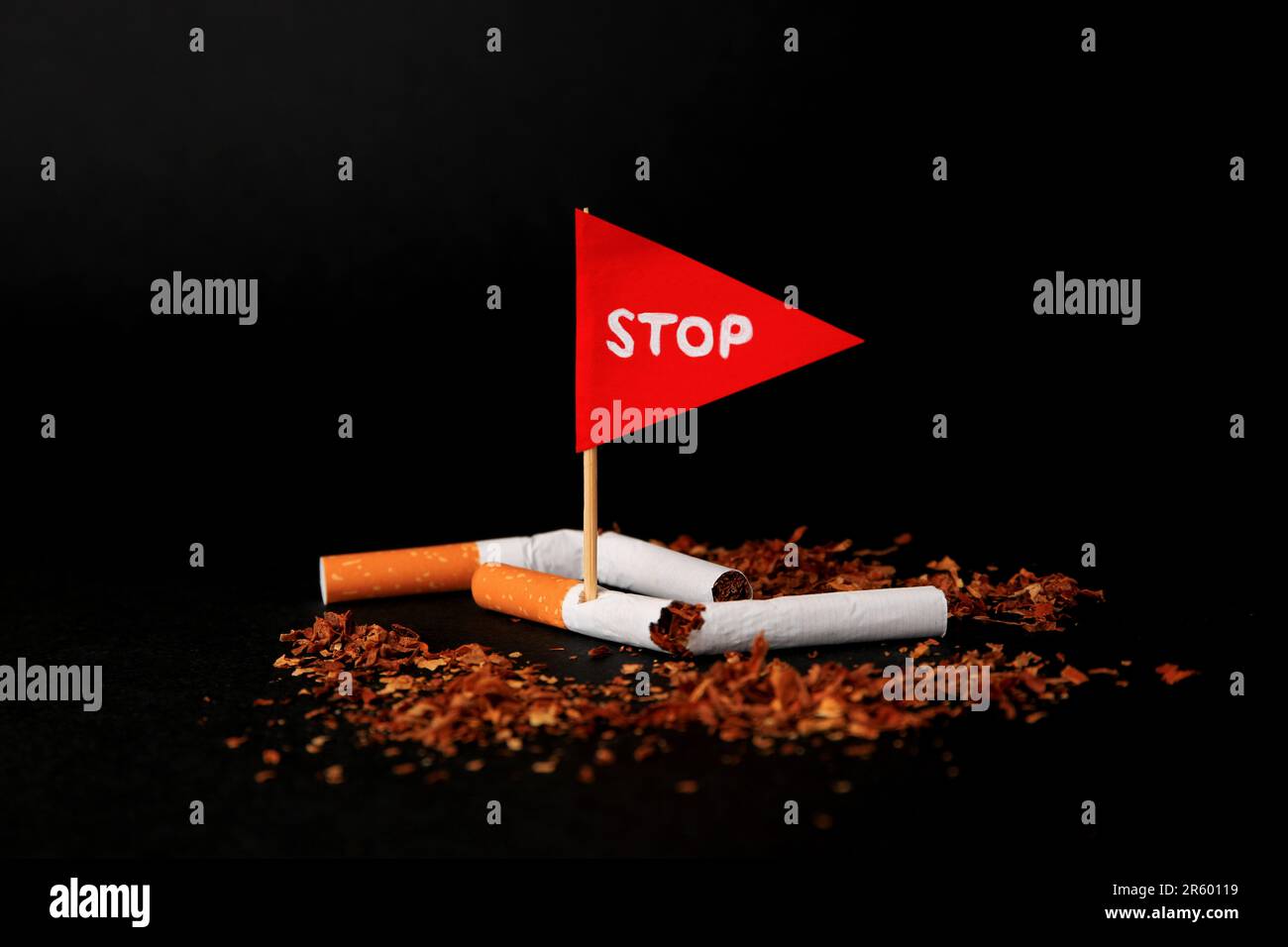 Broken cigarettes and red flag with word Stop on black background ...