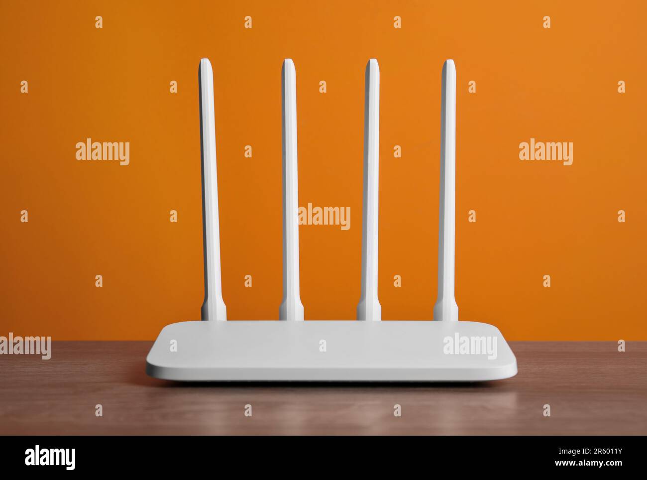 New modern Wi-Fi router on wooden table near orange wall Stock Photo ...