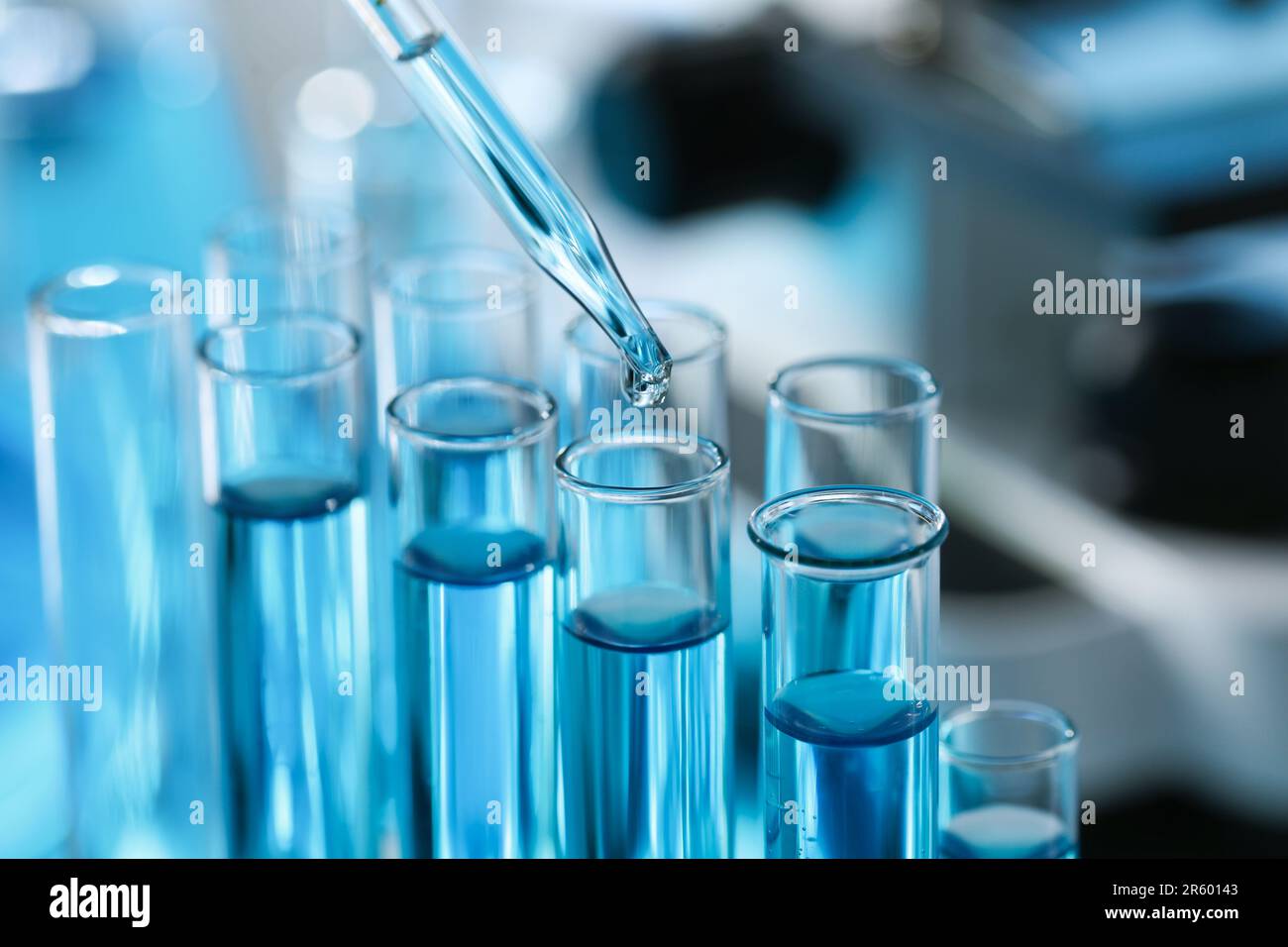 Dripping liquid from pipette into test tube in laboratory, closeup ...