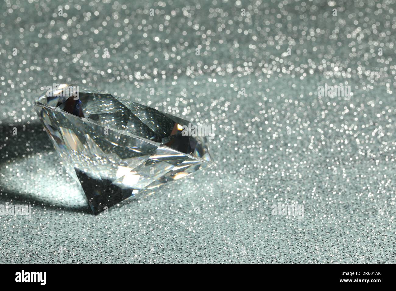 Beautiful dazzling diamond on silver glitter background, closeup. Space ...