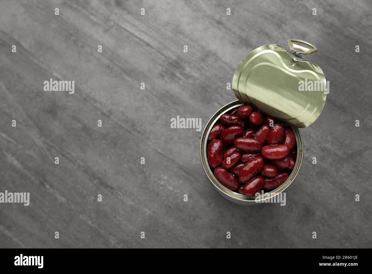 Tin can of canned red kidney beans on grey table, top view. Space for ...
