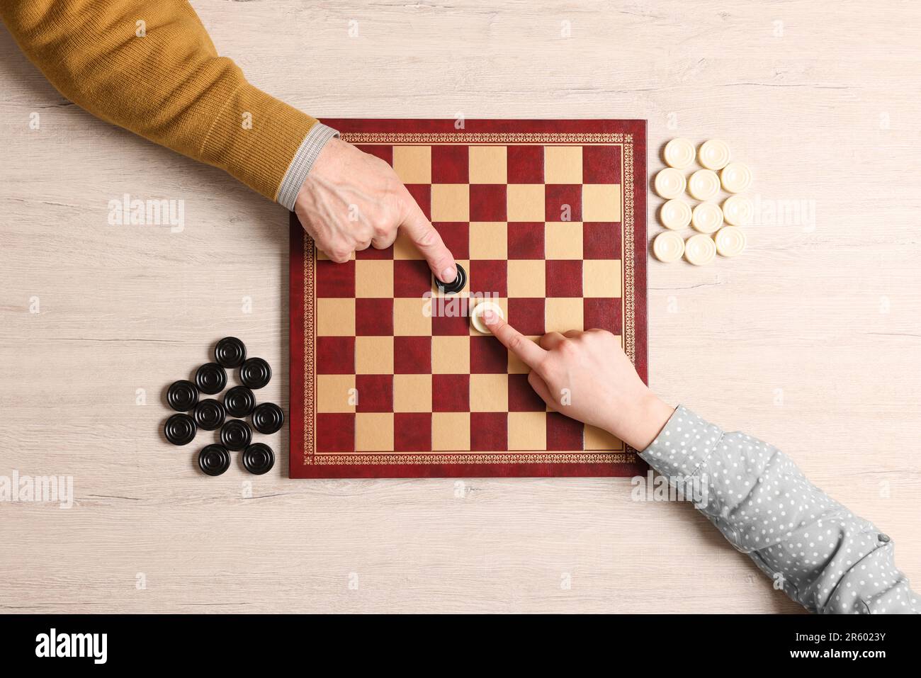 Senior man playing checkers with woman at white wooden table, top view ...
