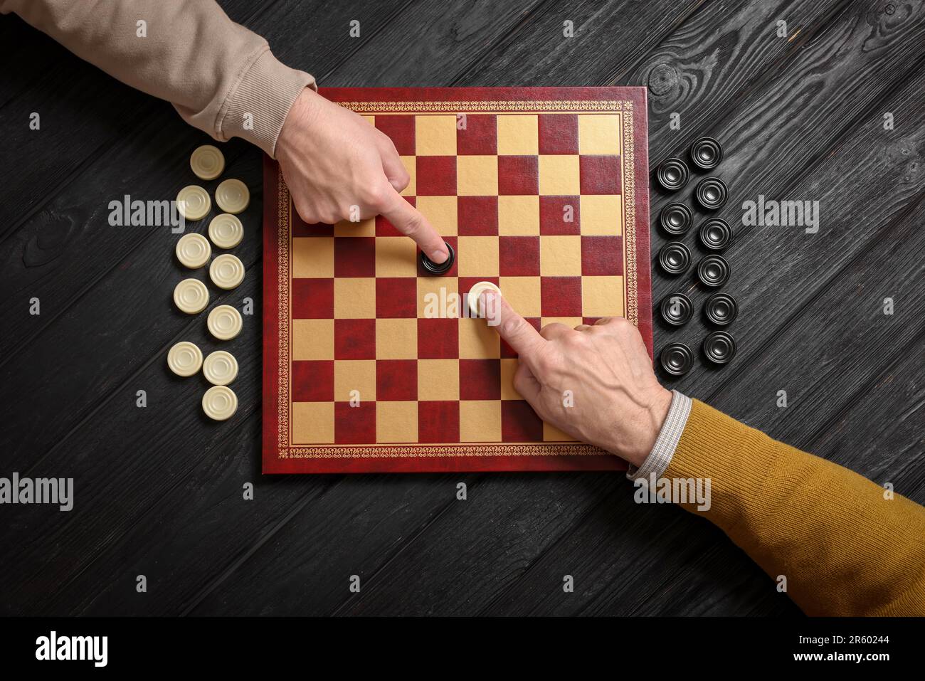 Man playing checkers with partner at black wooden table, top view Stock ...