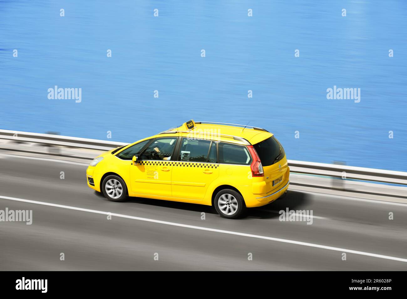 Yellow taxi cab driving at high speed on asphalt road near river ...