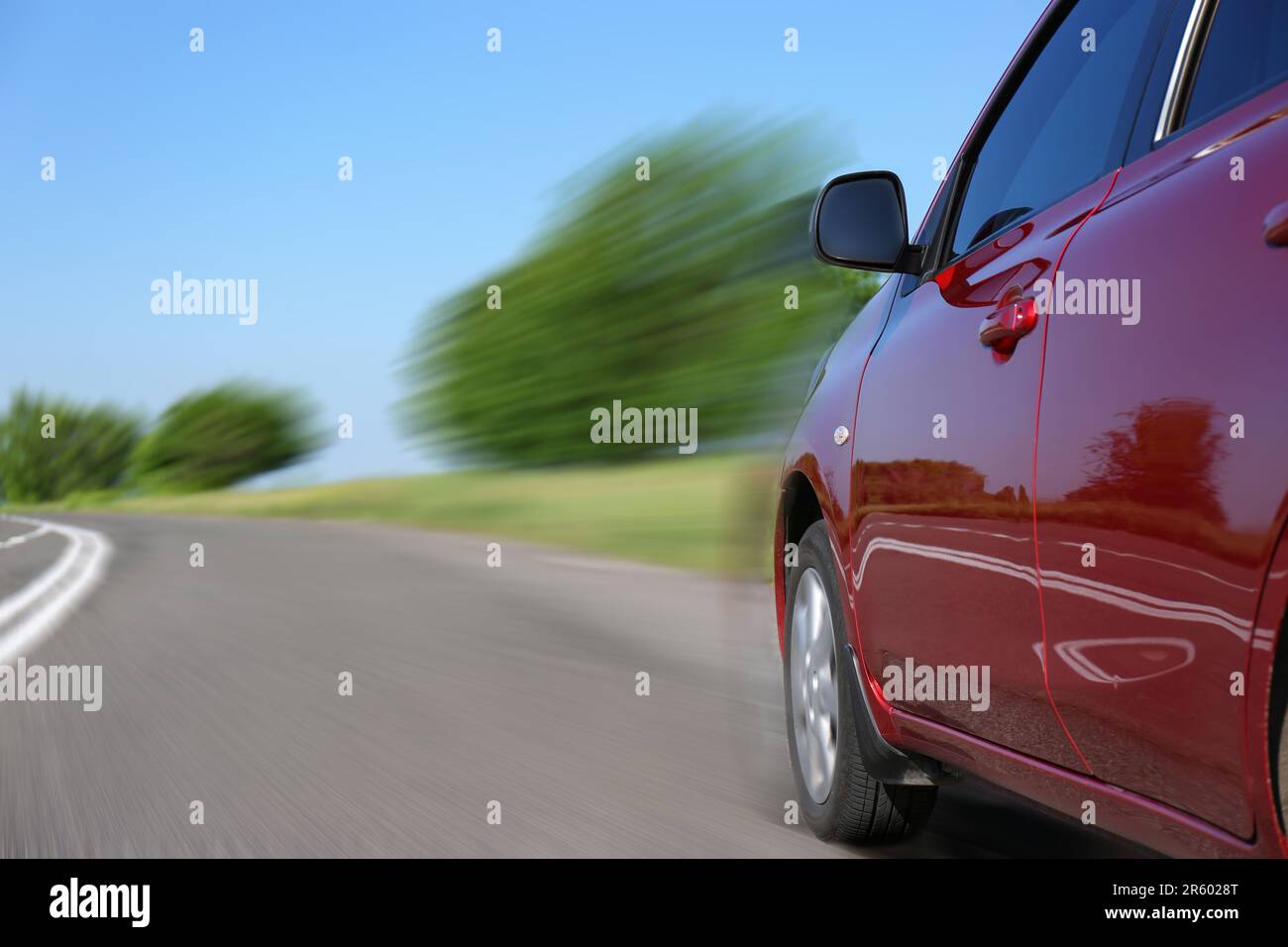 Red car driving at high speed on asphalt road outdoors, closeup with ...