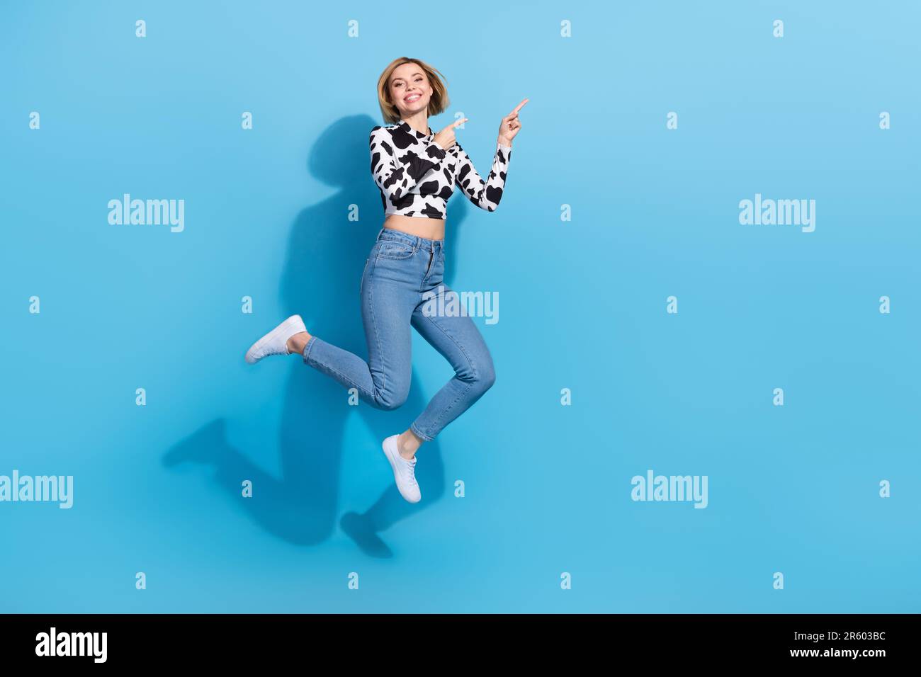 Full body portrait of carefree active lady jumping indicate fingers ...