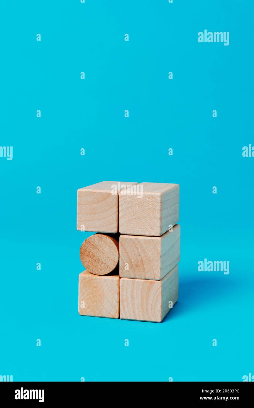 a cylindrical toy block in a stack of rectangular toy blocks, on a blue ...