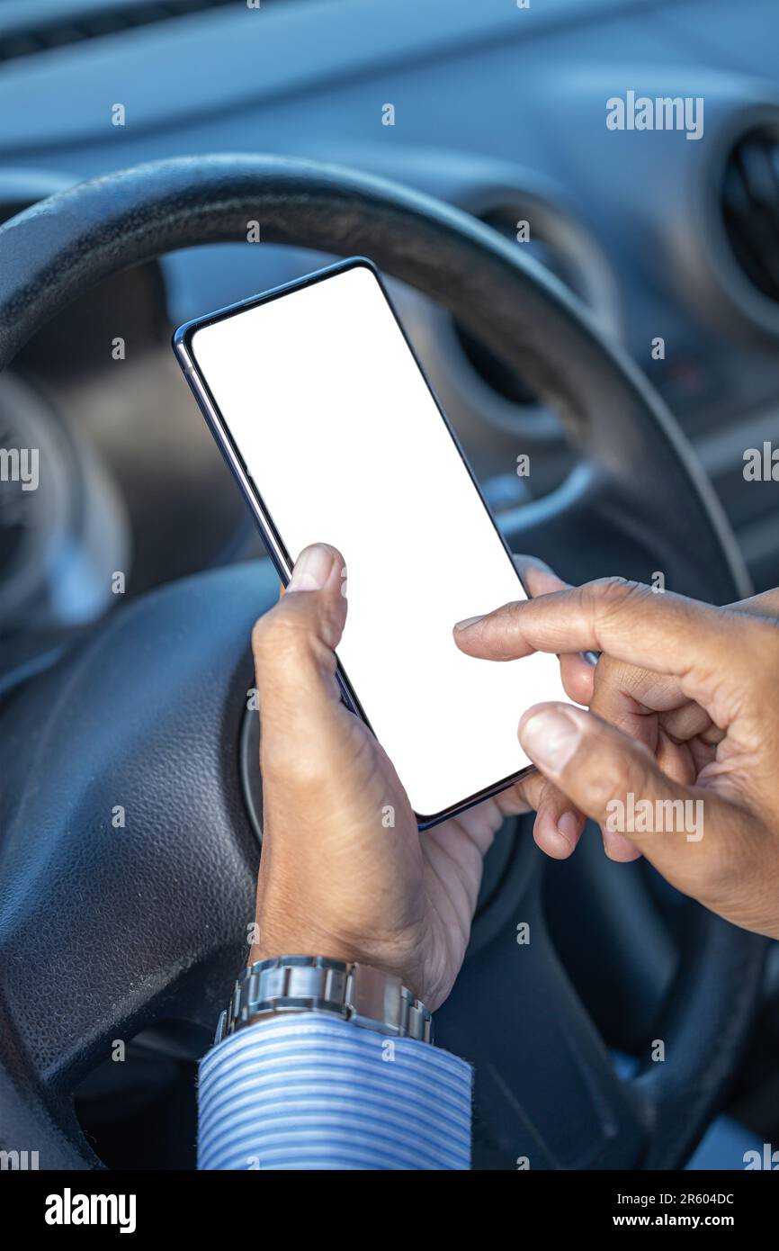 Detail of the hands of a driver holding a mobile phone with a blank ...