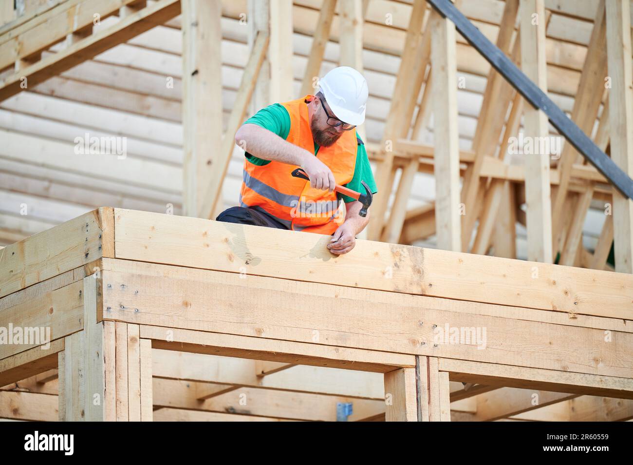 Carpenter constructing two-story wooden frame house. Man wearing ...