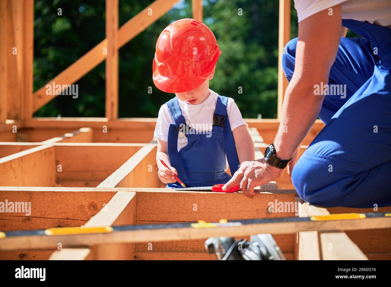 Father with toddler son constructing wooden frame house. Male builder ...
