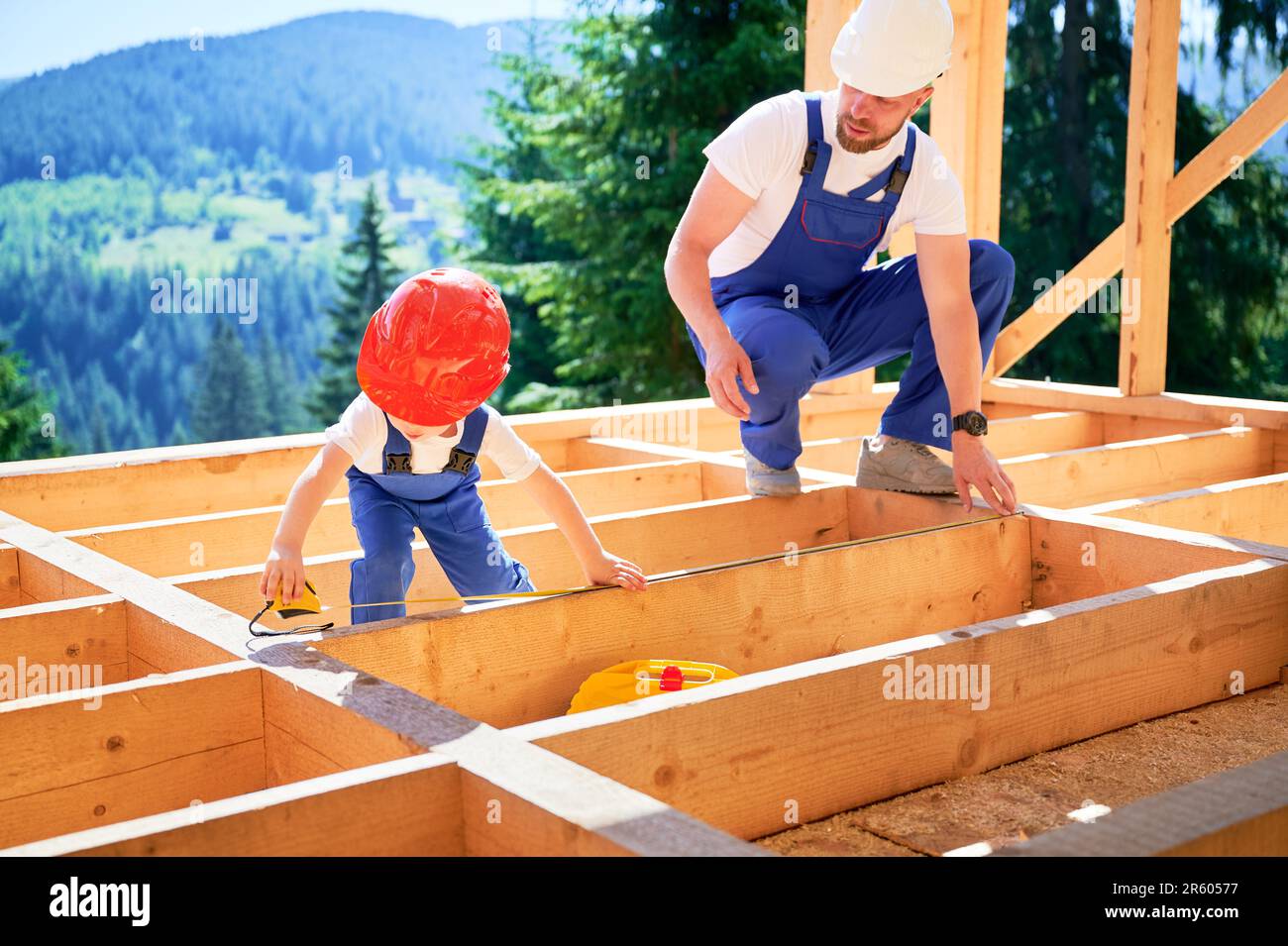 Father with toddler son building wooden frame house. Man worker ...