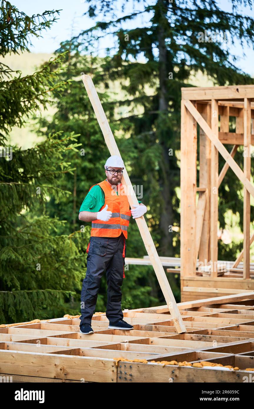 Carpenter builds wooden frame house near the forest. Bearded man with ...