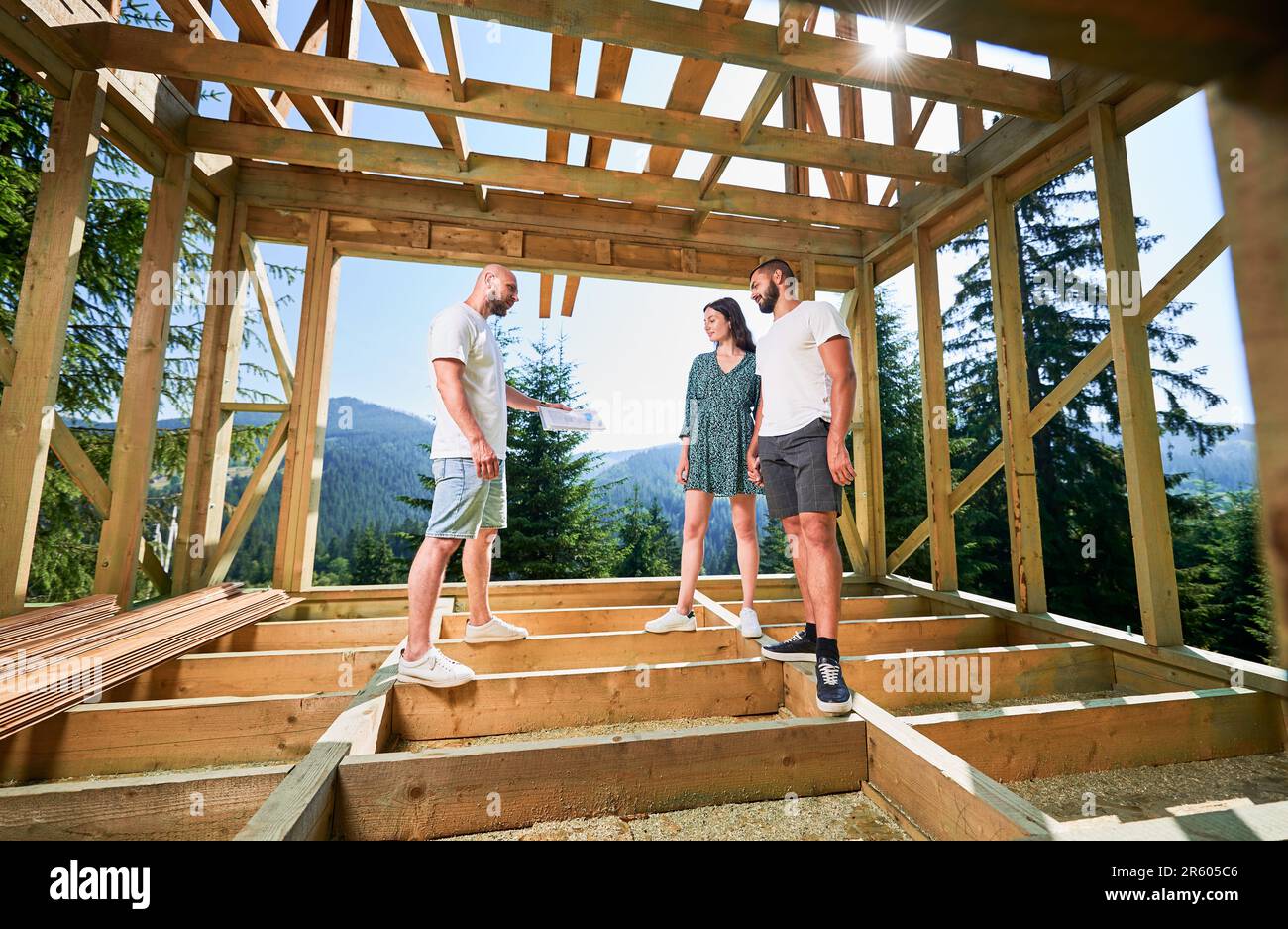 Man with plan showcases to couple the process of constructing wooden ...