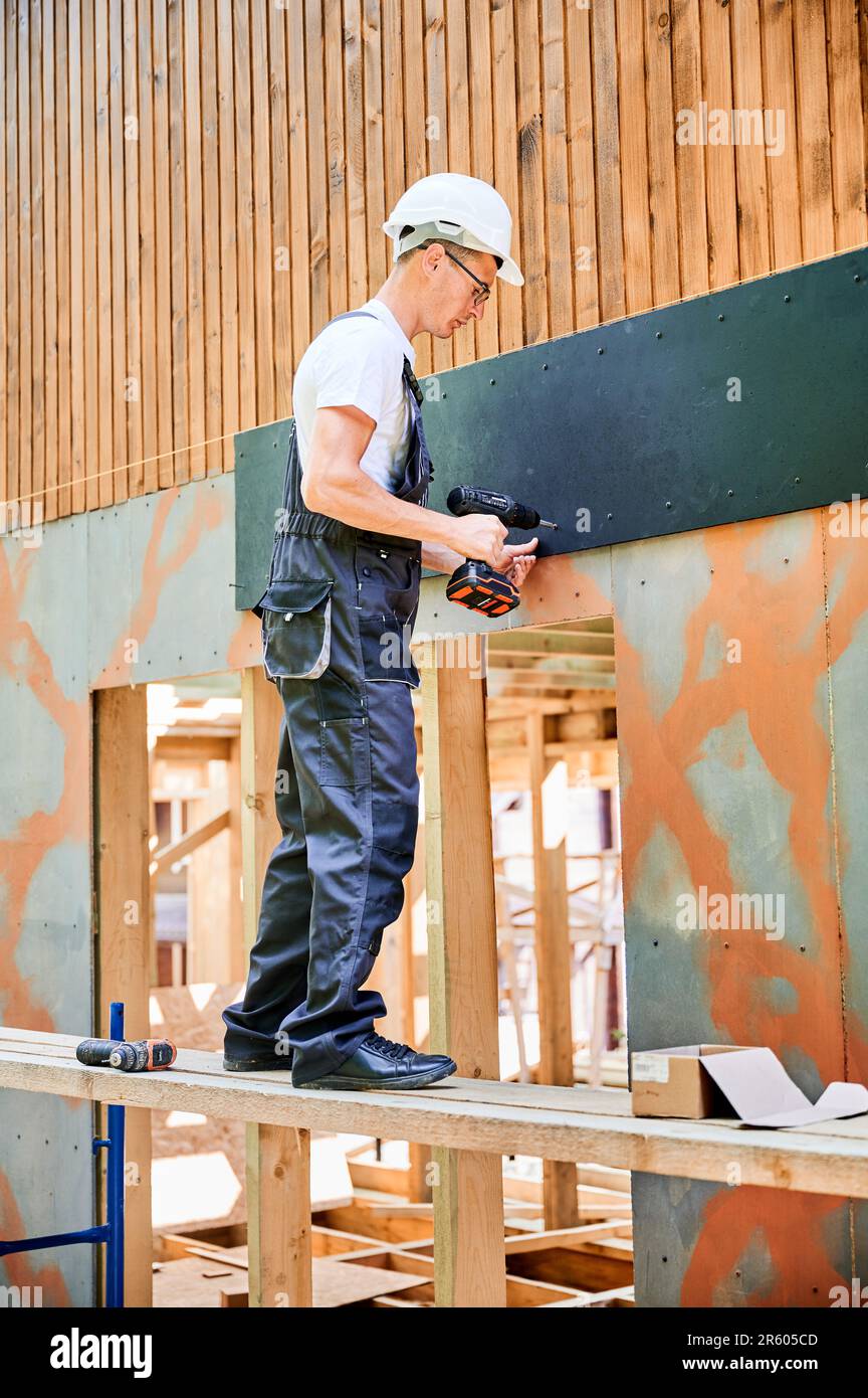 Carpenter constructing wooden framed house. Man worker in glasses ...