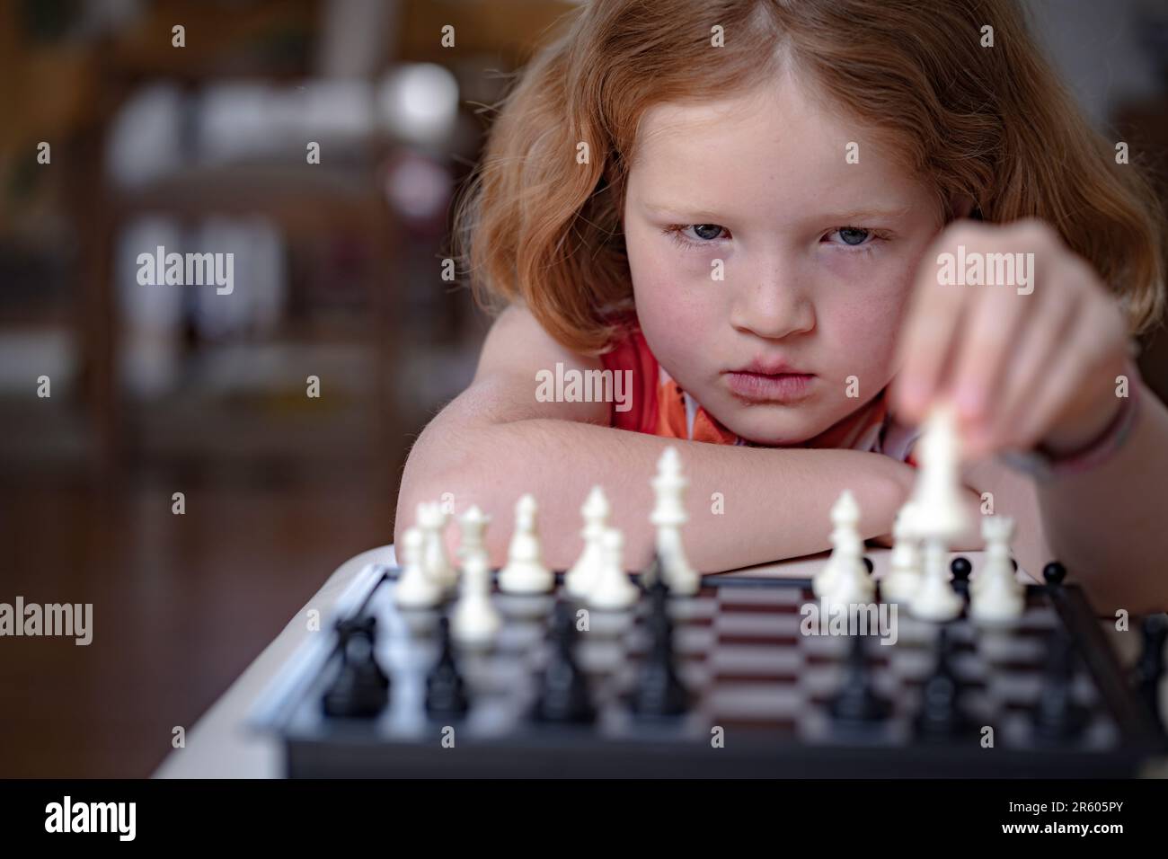 A red- haired girl playing chess, thinking pondering the next move. Differential focus, close up ...