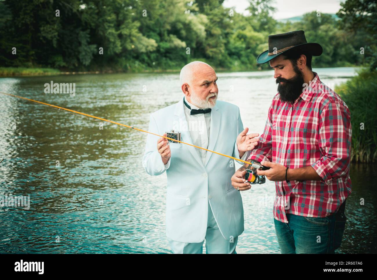 Two men friends fisherman fishing on river. Old father and son with rod ...