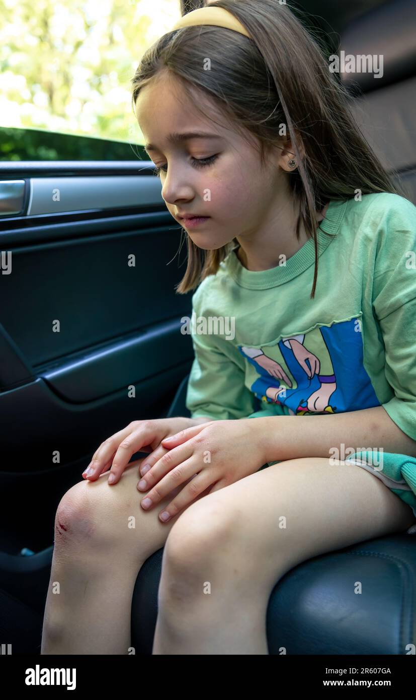 Close-up of little girl holding her bruised injured damaged knee with ...