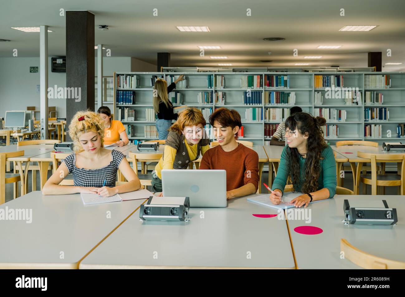 Group of multiethnic students discussing in library with laptop Stock ...