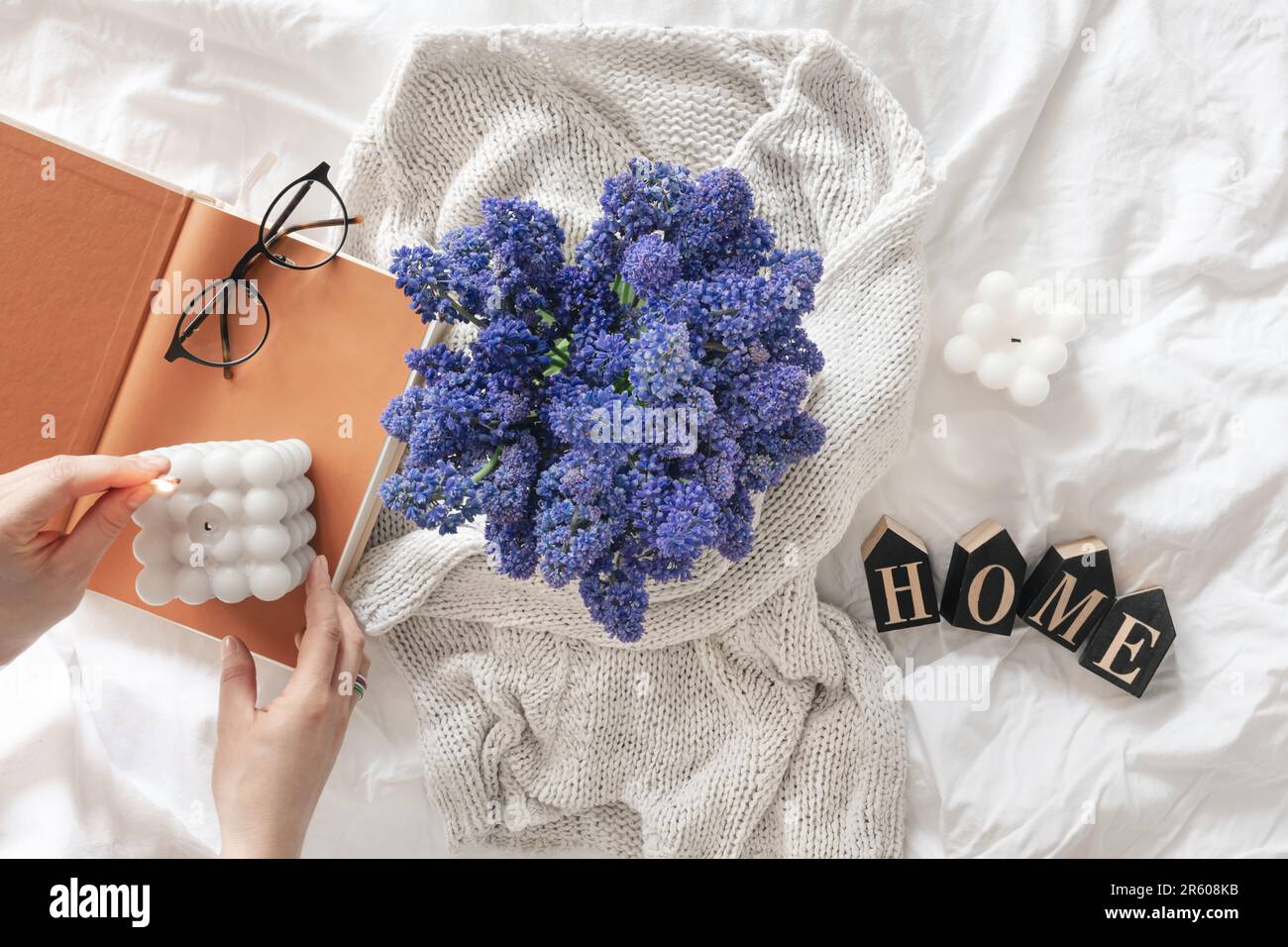 A bouquet of flowers, candles and a decorative word Home in a white bed ...