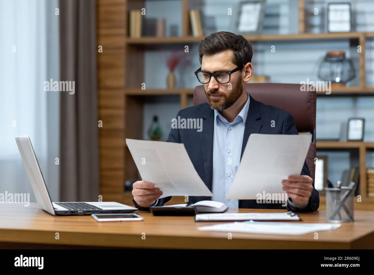 Serious and focused financier accountant on paper work inside office ...