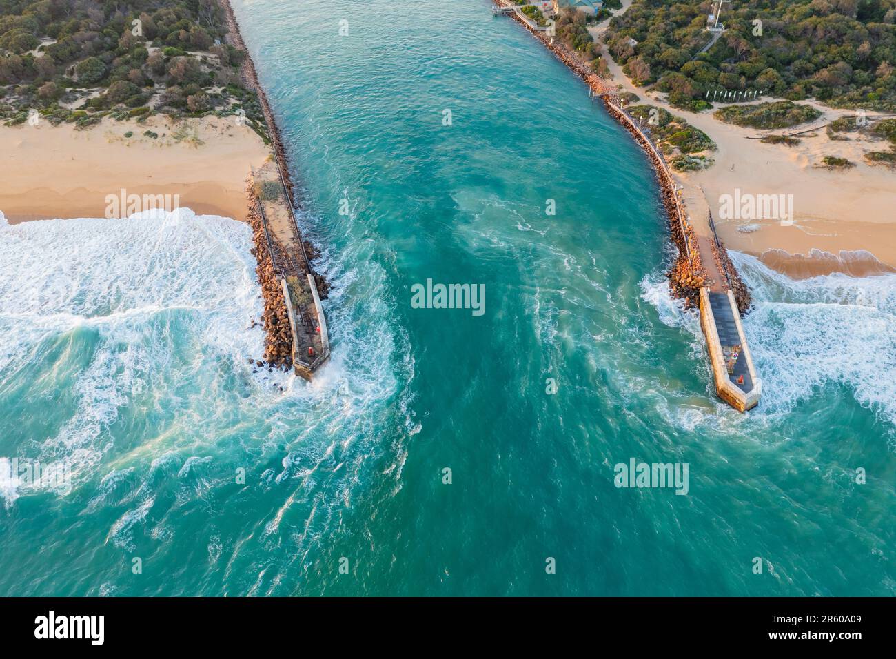 Aerial view of water rushing inland through breakwater walls with beach ...