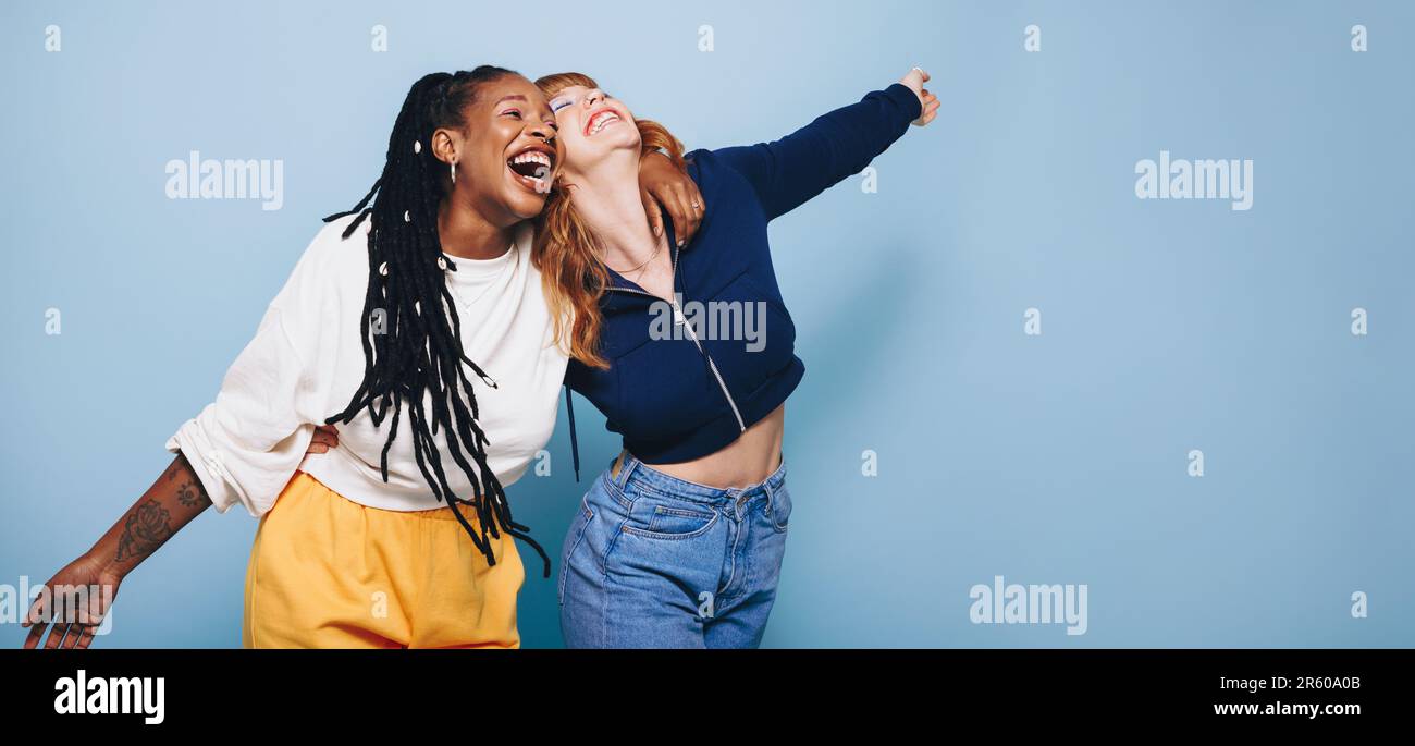 Two happy best friends laughing and having a good time while embracing ...