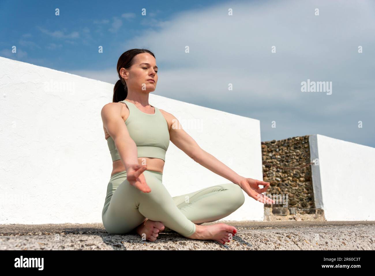 Mid adult woman meditating and practicing yoga outside in the summer ...