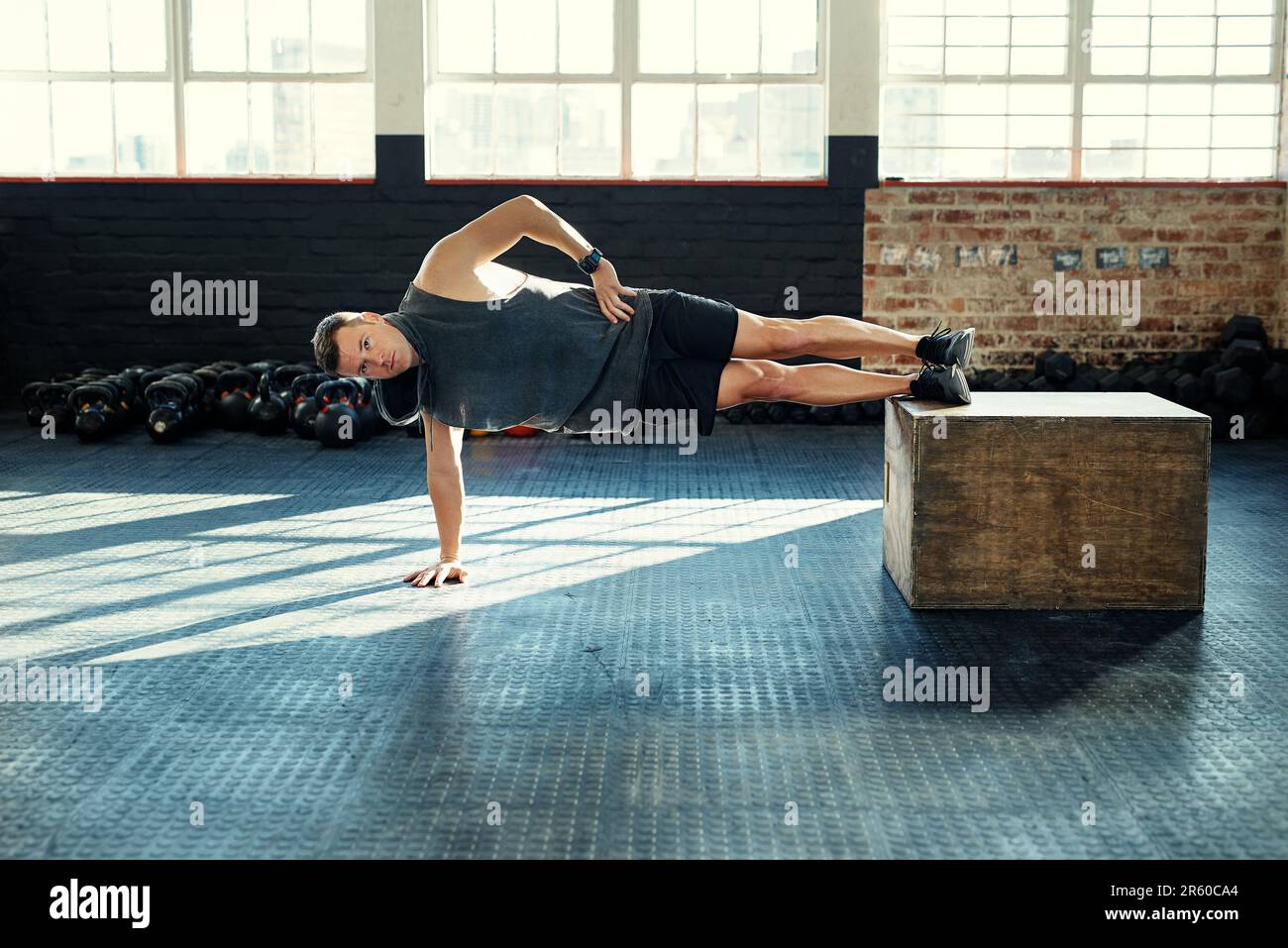 Planking his way to fitness. a young man doing a side plank with a ...