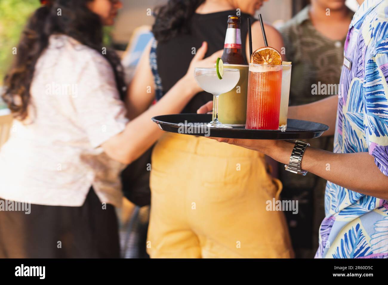 Waiter serving cocktail for group of people celebrating Stock Photo - Alamy