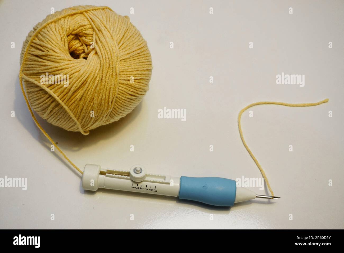 Punch knitting tools with yarn on isolated background Stock Photo - Alamy