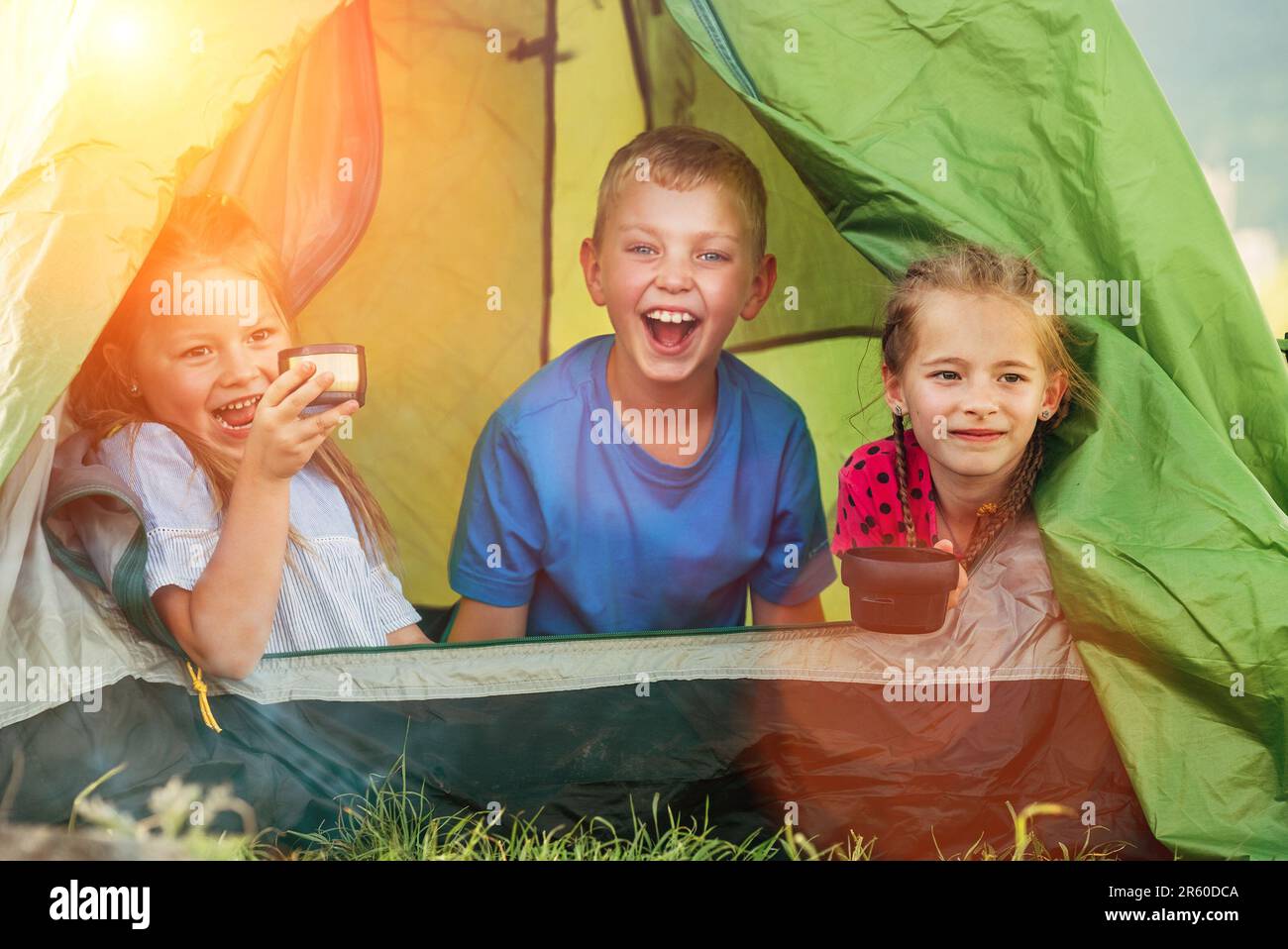 Little girls sisters and brother boy sitting inside green camp tent ...