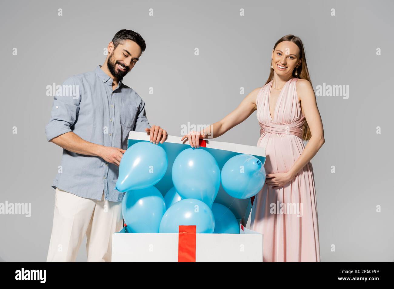 Smiling and elegant pregnant woman opening big gift box with blue ...