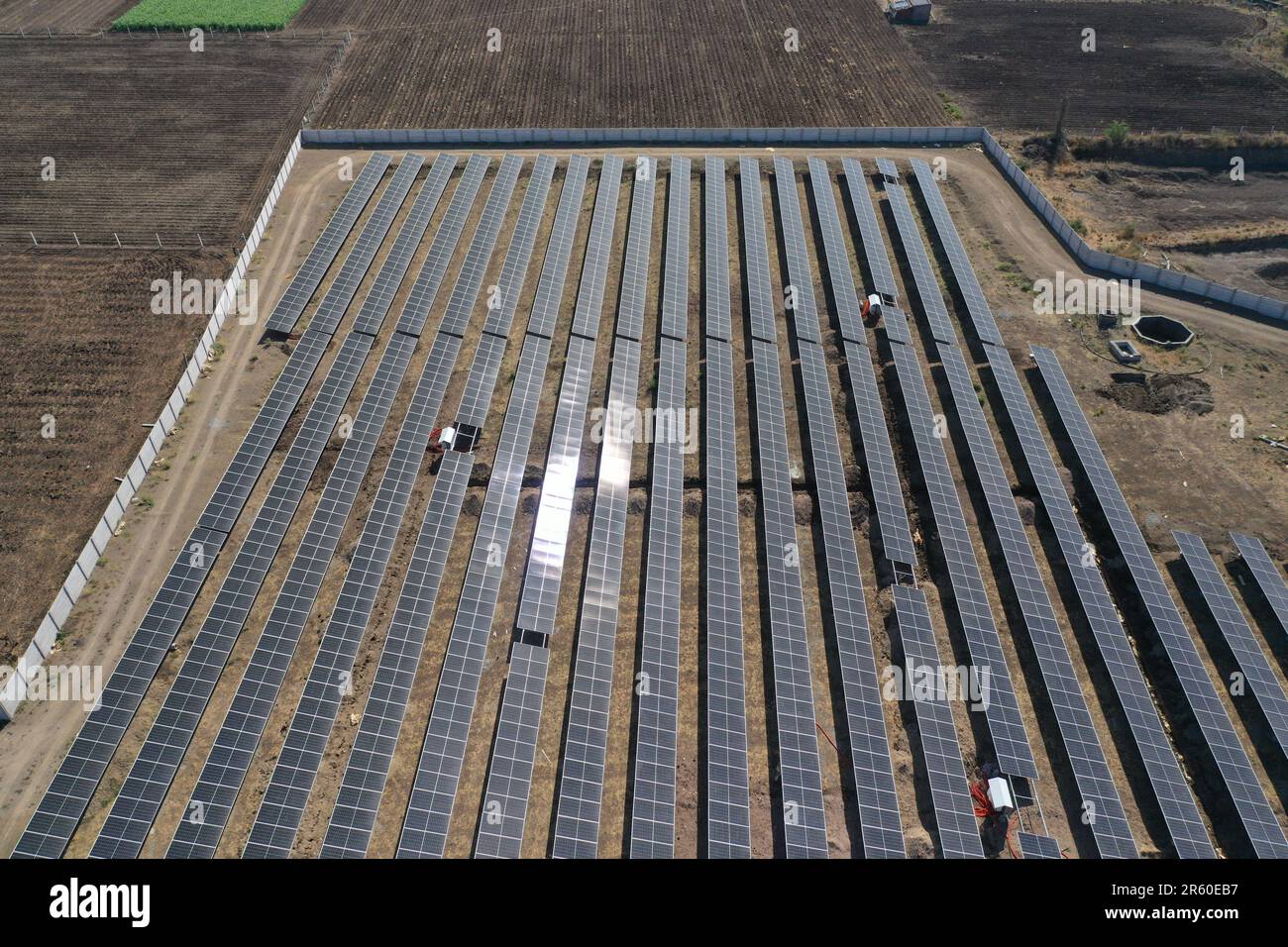 An aerial view of a large-scale solar farm with an array of black solar ...