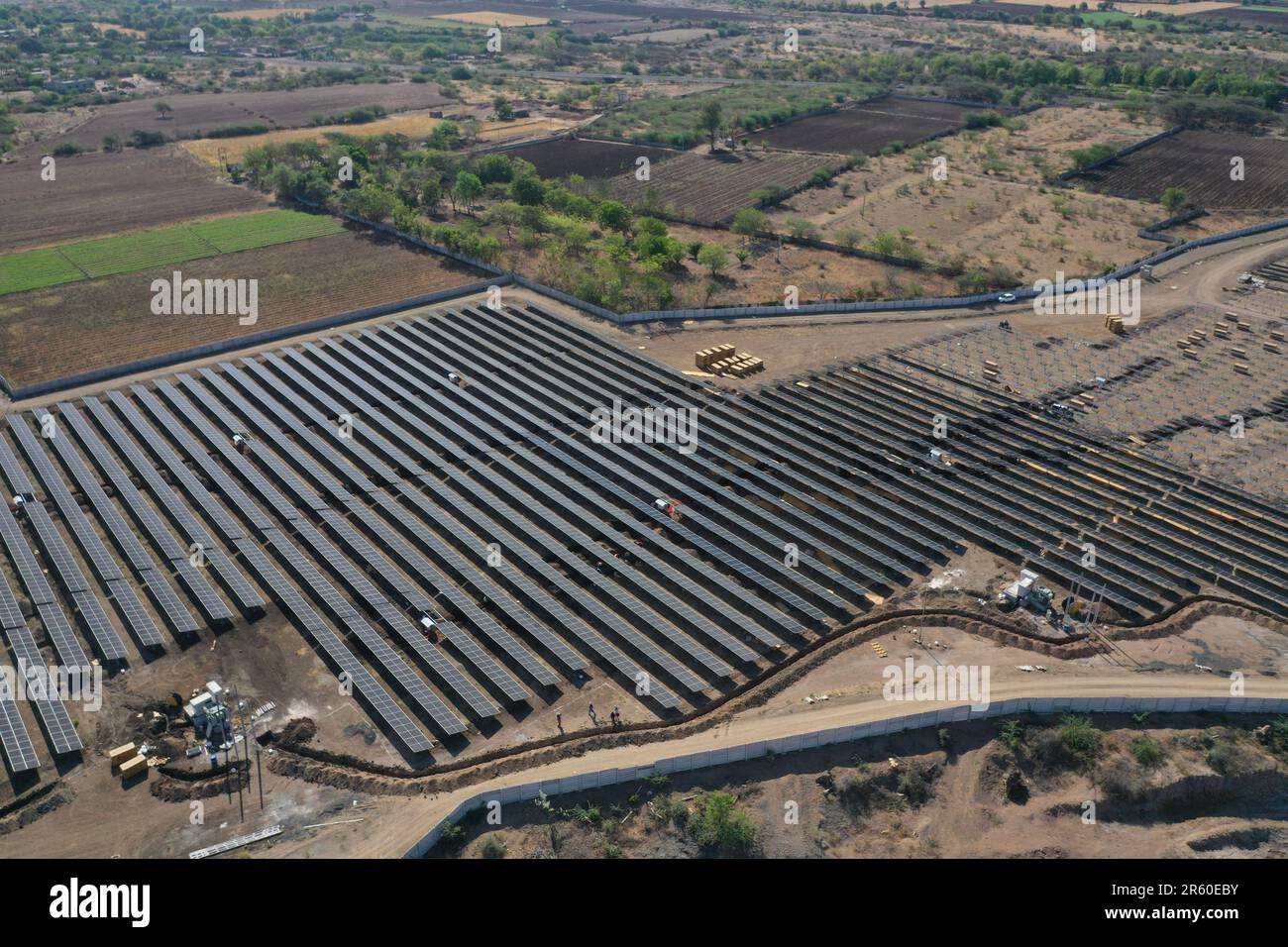 An aerial view of a large-scale solar farm with an array of black solar ...