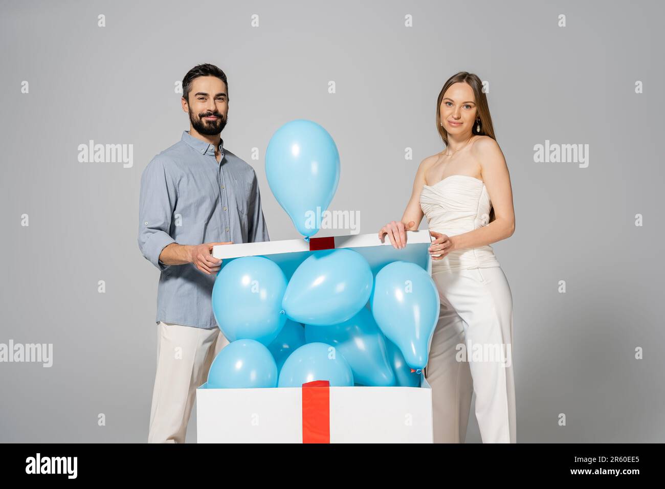 Positive and stylish expecting parents looking at camera while opening ...