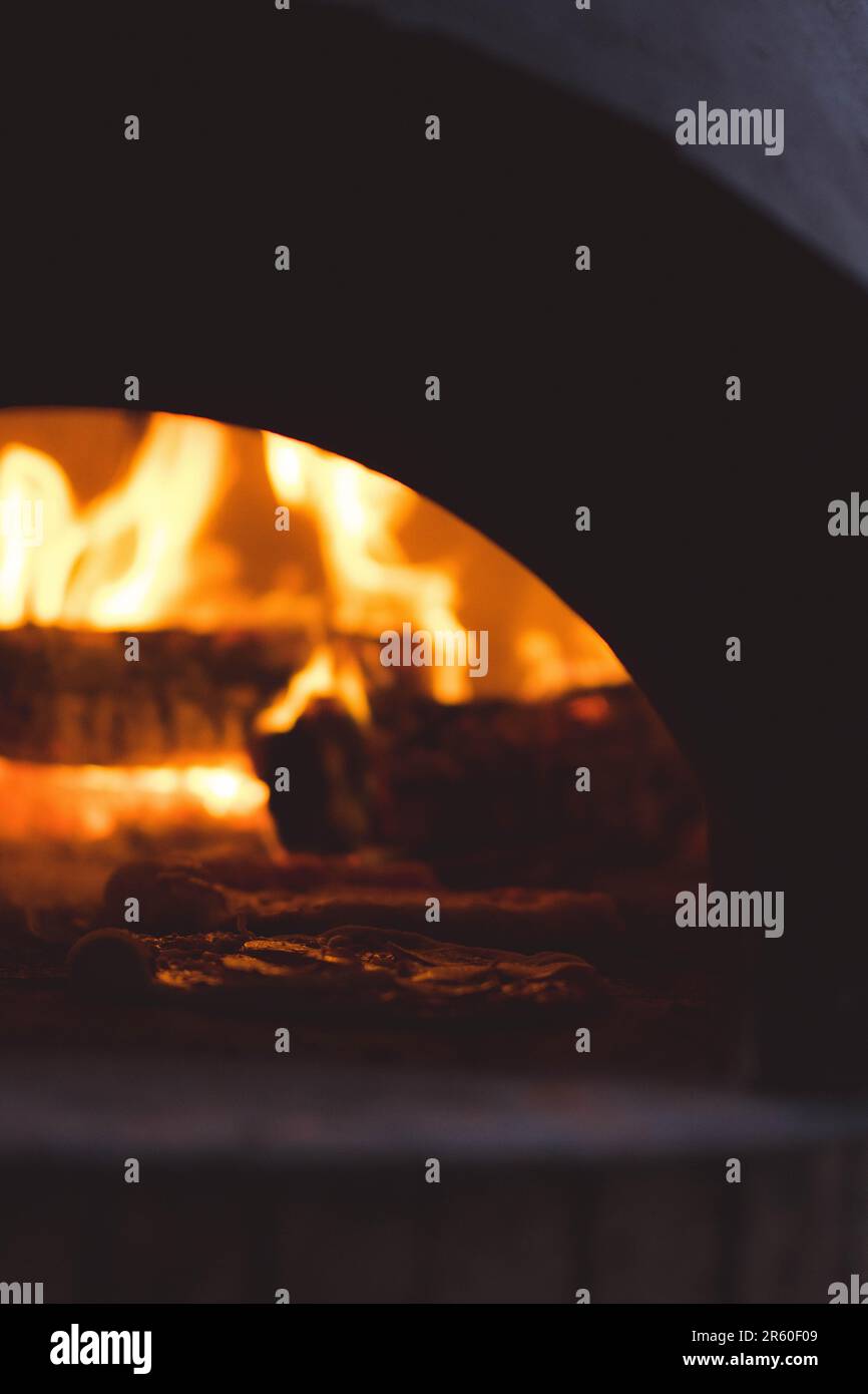 A distant view of a pizza oven with flames inside, giving off a warm ...