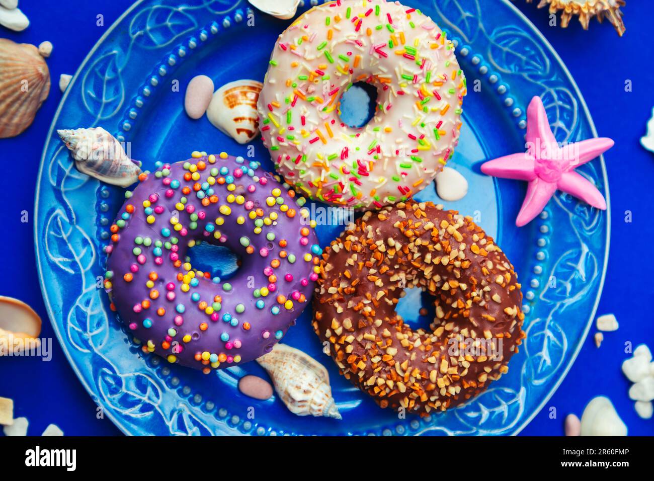 Assorted donuts in a plate on a blue background. Around them are ...