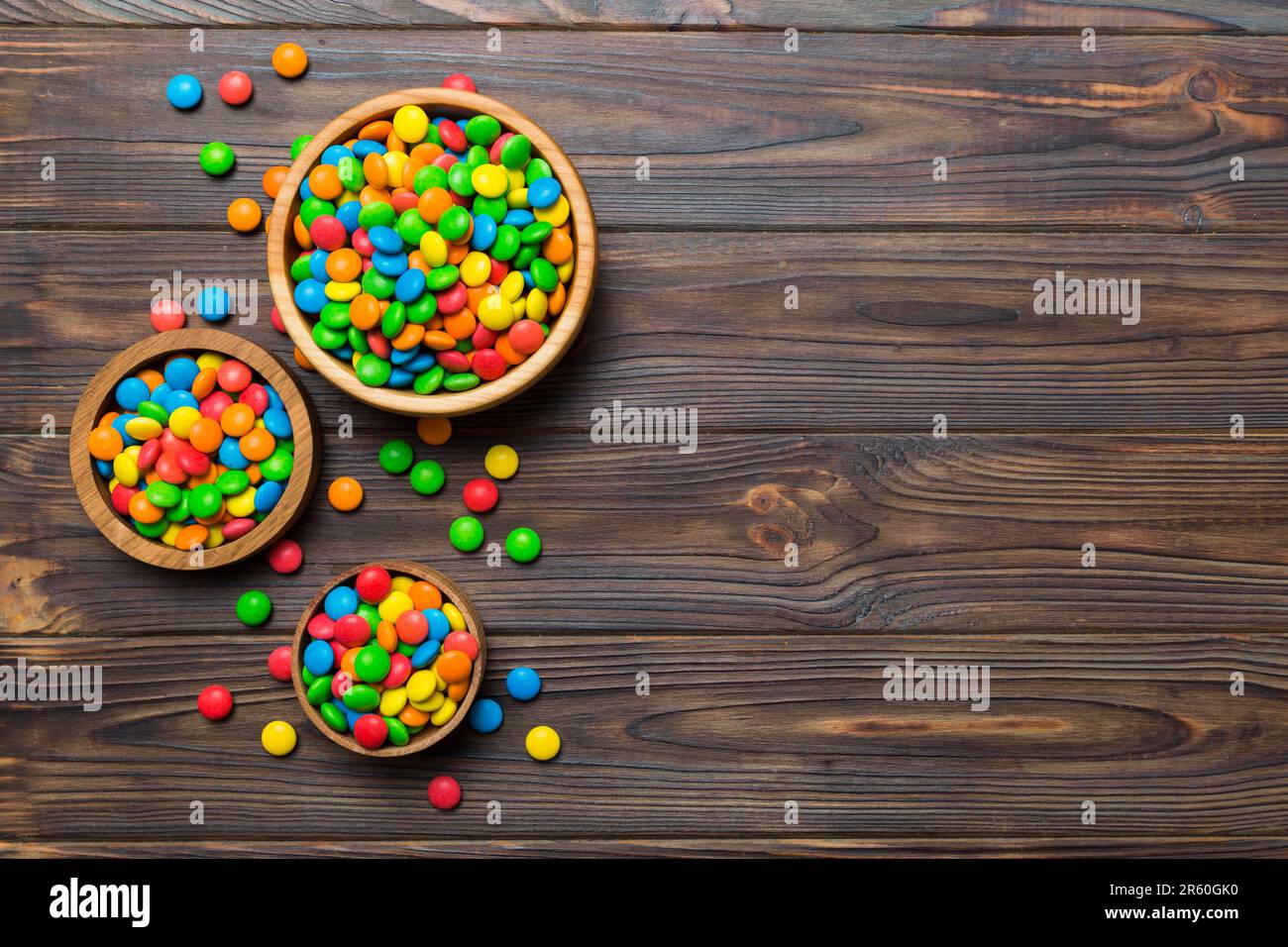 different colored round candy in bowl and jars. Top view of large ...