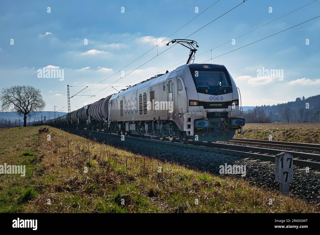 A vintage train moves along the tracks in a landscape, with lush green ...