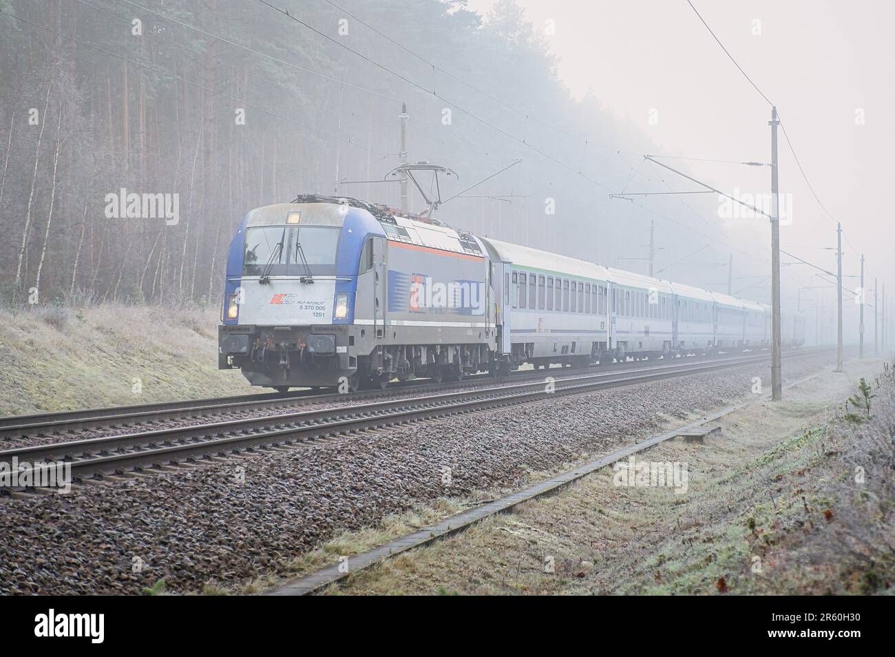 A vintage train moves along the tracks in a landscape, with lush green ...